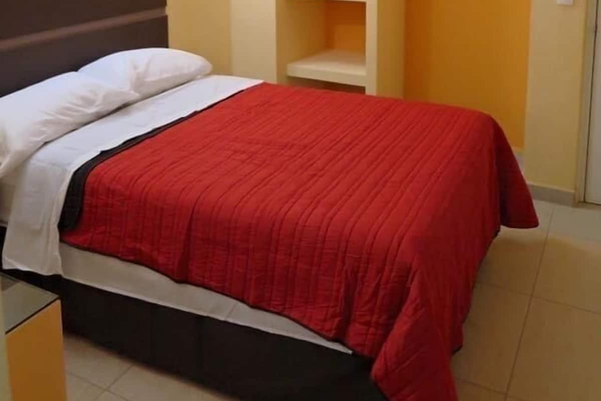 Quarto com cama, guarda-roupa e ventoinha no teto.