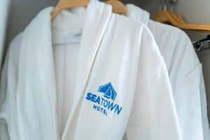 Um roupão branco com o logotipo do Hotel Seatown pendurado em um cabide de madeira.