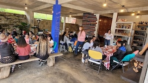 Um espaço de refeições informal com paredes de pedra, bancos de madeira e diversas opções de assento.