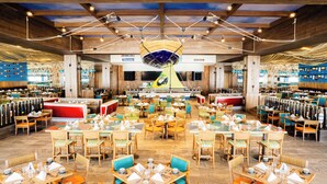 Um restaurante espaçoso com várias áreas de refeições, mobiliário de madeira e uma ilha central.