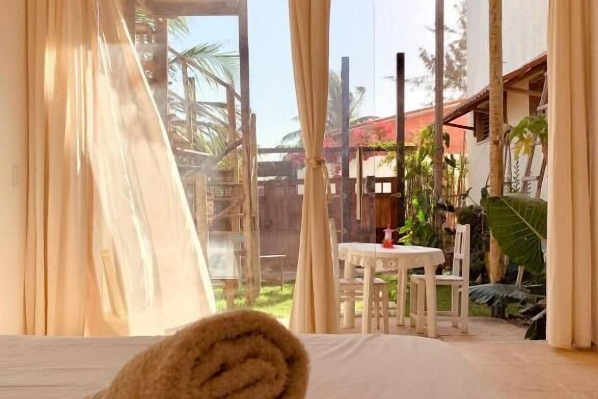 Quarto de hotel com cama, mesa, cadeiras e vista para o exterior.