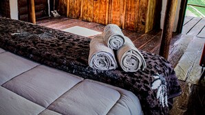 Quarto aconchegante com uma cama grande, uma rede e um espaço bar em madeira.