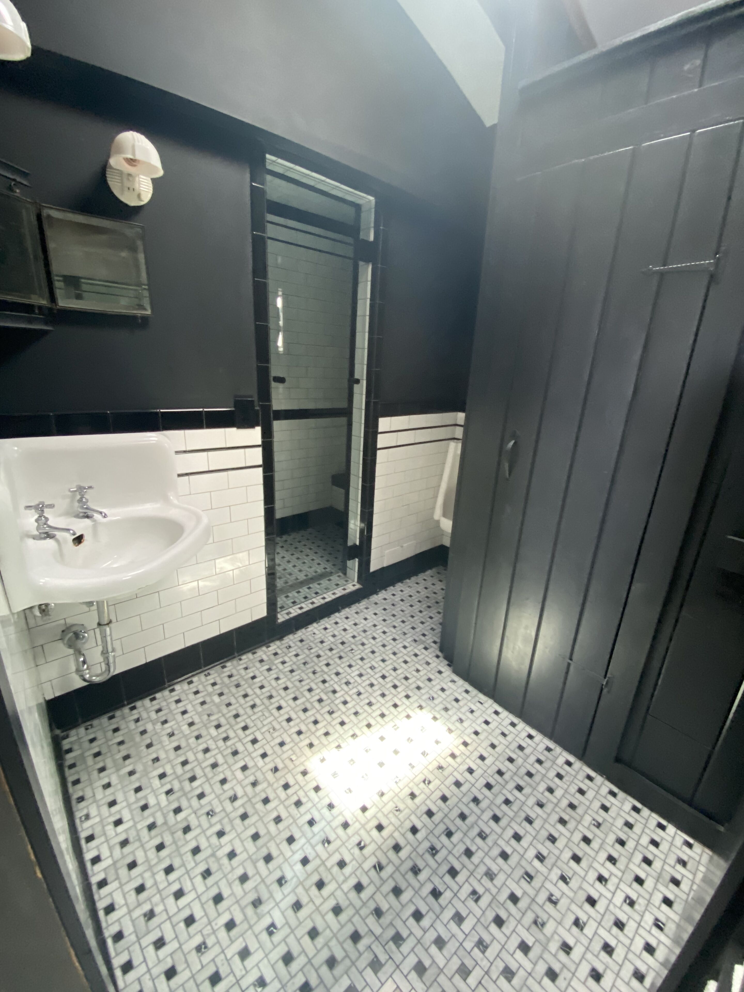 Casa de banho com lavatório branco, espelho e chão em mosaico.