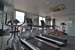 Uma academia com esteiras, bicicleta ergométrica e aparelho de supino.