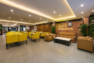 Interior de restaurante moderno com assentos em tons de amarelo e castanho, um letreiro de neon e uma parede de destaque em madeira.