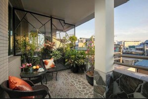 Uma varanda com mesa, cadeiras e plantas em vasos.