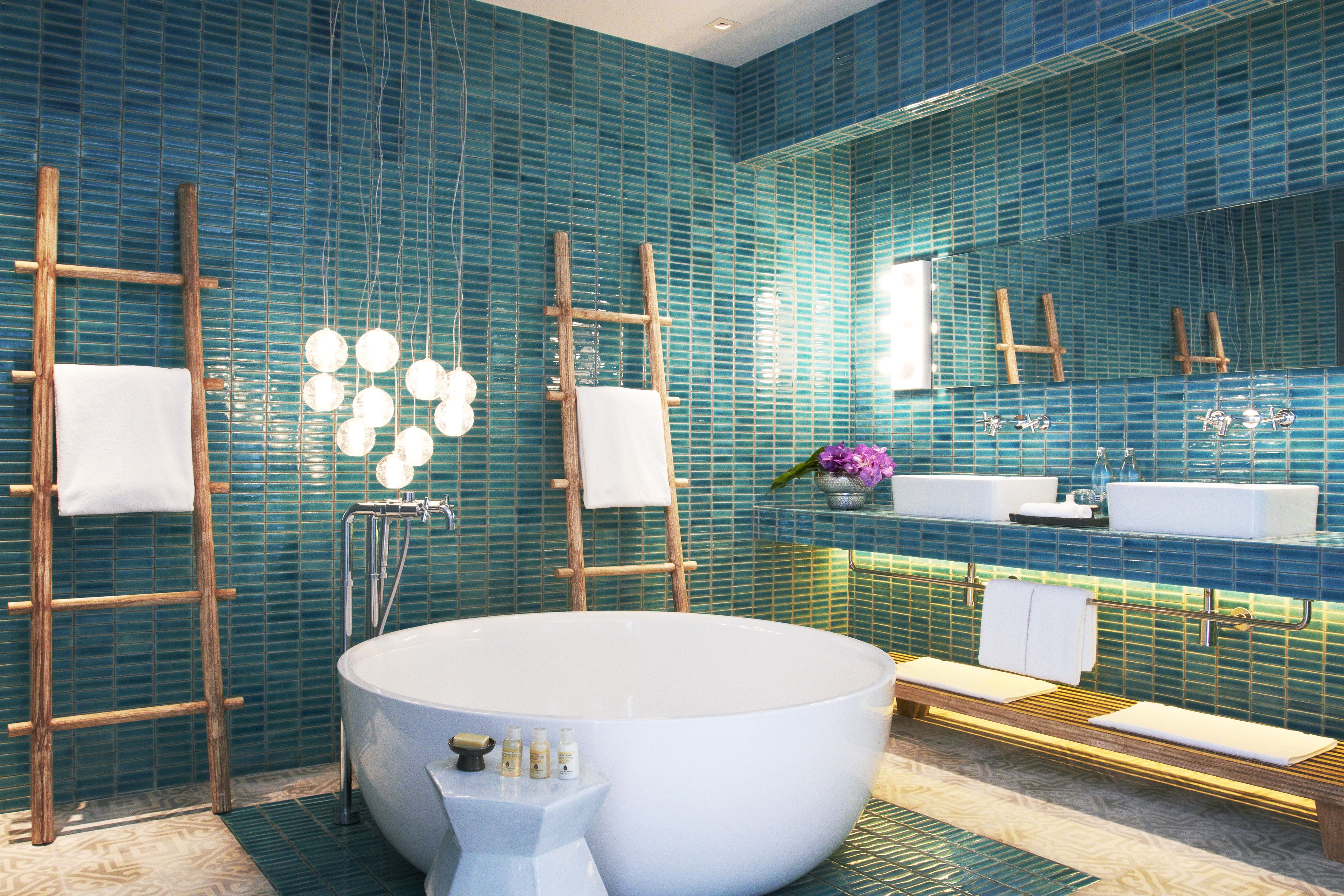 Casa de banho moderna com uma banheira grande, escadas de madeira e espelho com revestimento de azulejos azuis.