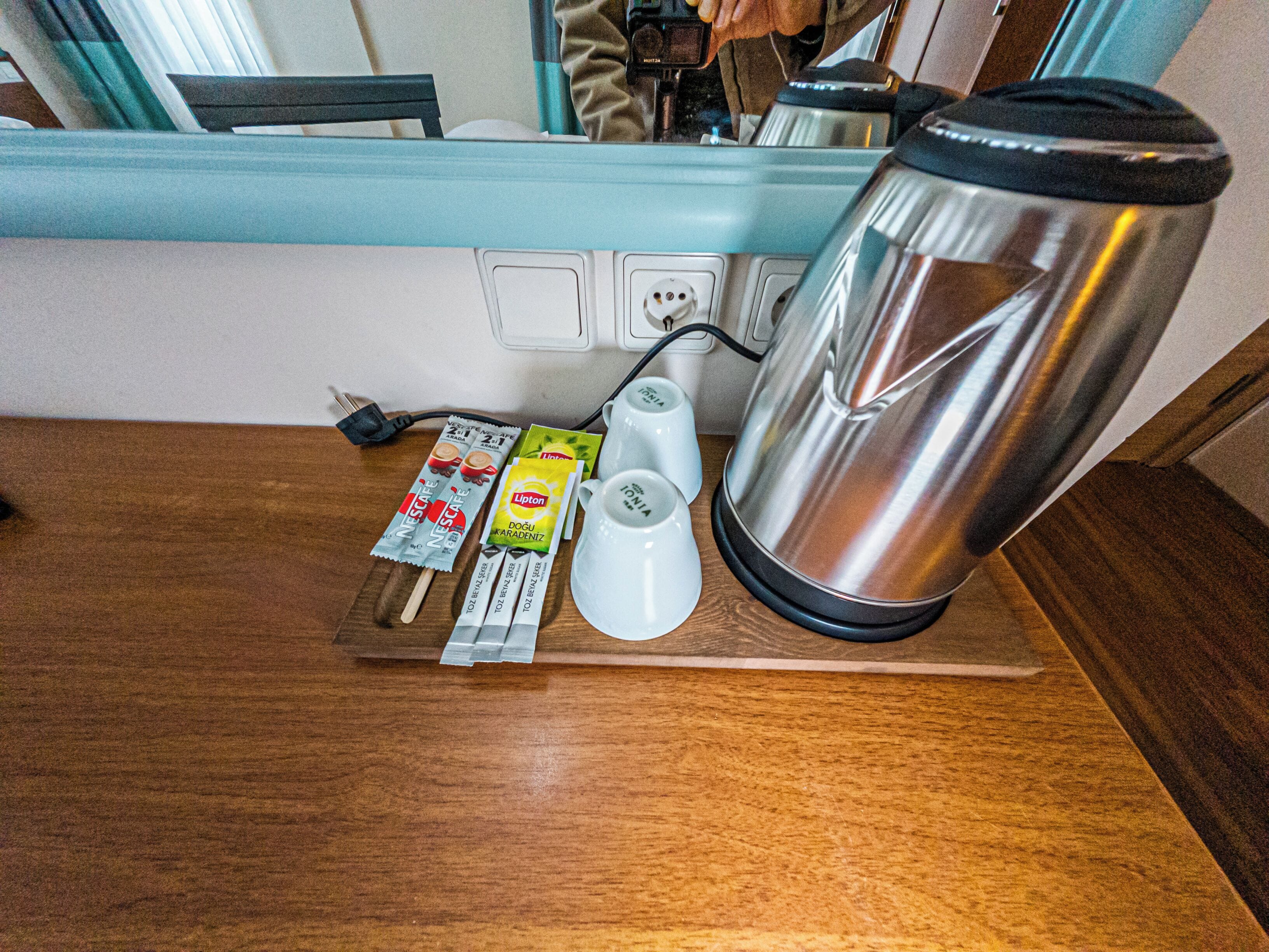 Uma bancada de cozinha com uma cafeteira, um bule e alguns sachês de café.