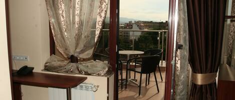 Uma varanda com mesa, cadeiras e vista para edifícios ao longe.