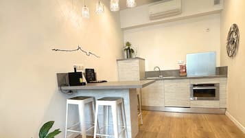 Uma cozinha moderna com ilha central, luminárias pendentes, forno embutido e uma janela ampla.
