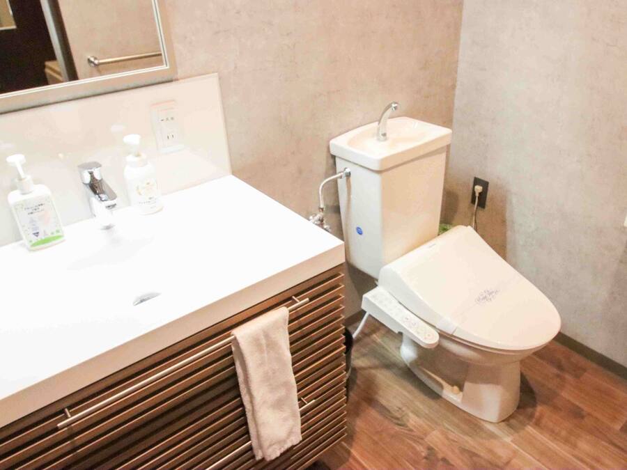 Casa de banho com uma sanita, lavatório branco e espelho.