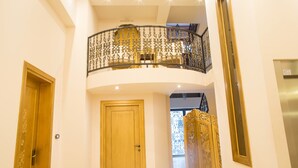 Amplo interior com uma escadaria curva, uma porta de madeira e um portão decorativo.