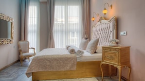 Quarto com cama grande, mesa de cabeceira, cadeira e espelho.