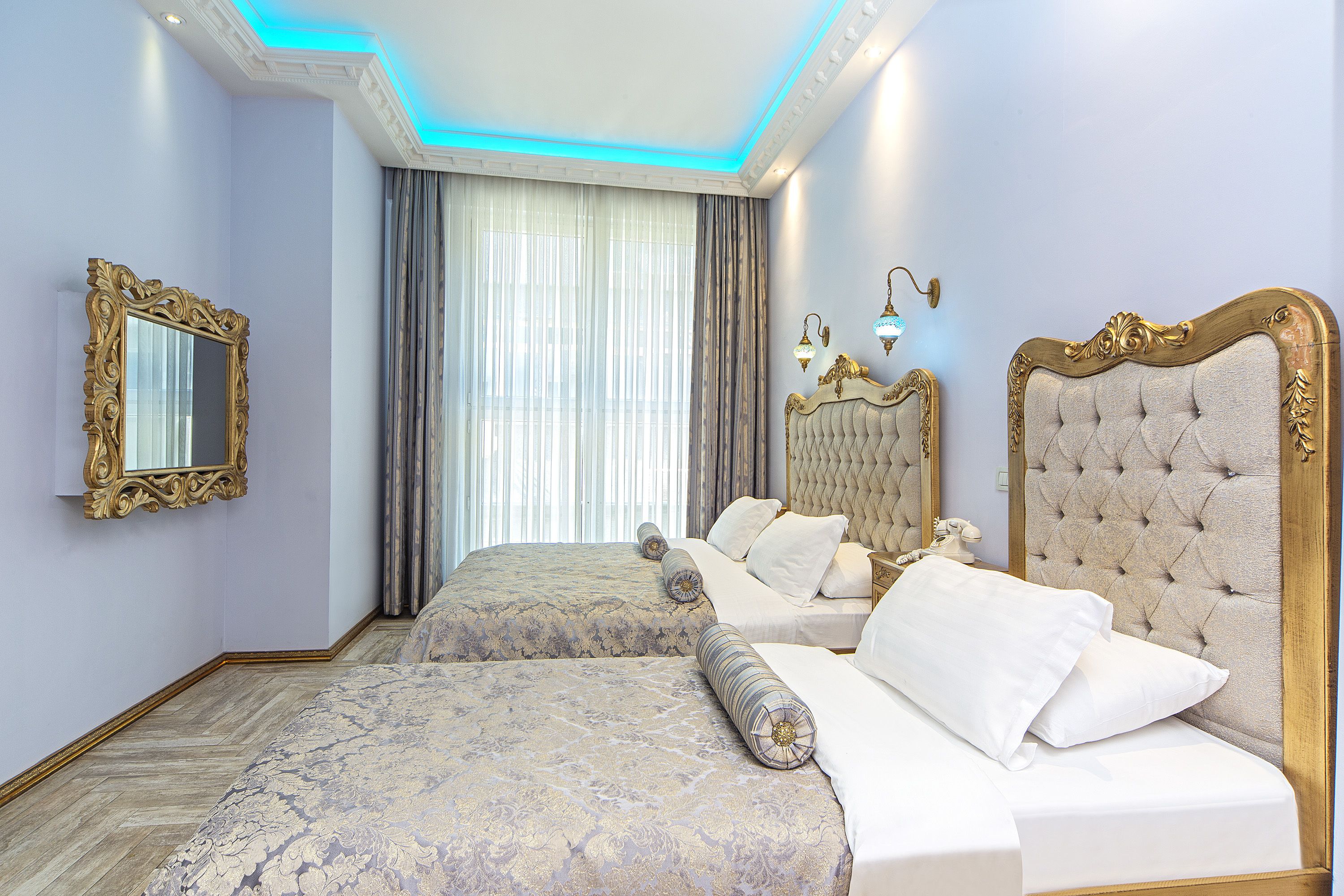 Quarto com duas camas, um espelho grande e um candelabro.