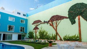 Um edifício moderno com piscina, área de estar ao ar livre e um mural de árvores.