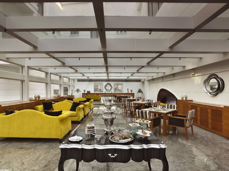 Uma sala de jantar ampla com pé-direito alto, móveis modernos e uma mesa central posta para refeição.