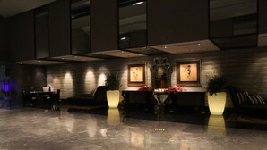 Um lobby moderno com piso de mármore, balcão de recepção, área de estar e obras de arte emolduradas nas paredes.