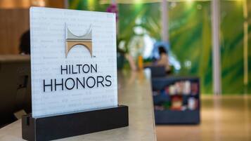 Uma receção com uma placa a indicar "Hilton HHONORS" e um logótipo.
