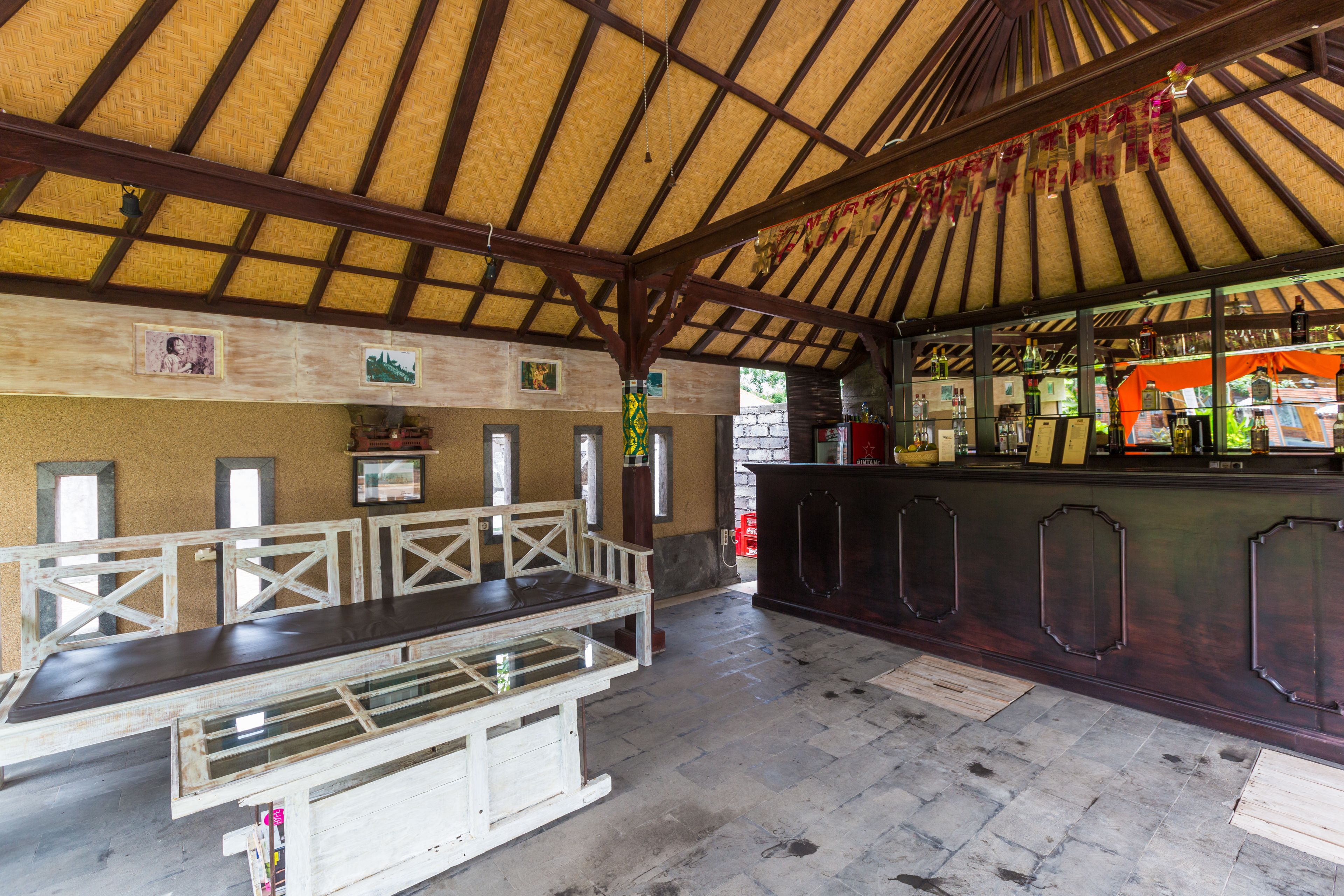 Uma área de estar coberta ao ar livre, com bancos de madeira e um balcão de bar.