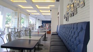 Um restaurante moderno com paredes de tijolos brancos, um banco acolchoado azul e teto com iluminação embutida.