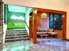 Um interior moderno com um sofá verde, um banco de madeira e uma escadaria com degraus de mármore.
