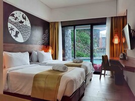 Quarto de hotel com duas camas, uma escrivaninha, televisão e uma janela grande com vista para o verde.