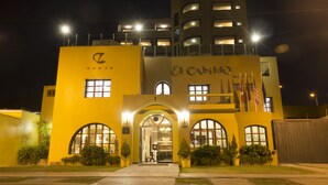 Um hotel com fachada amarela, janelas em arco e uma entrada imponente.