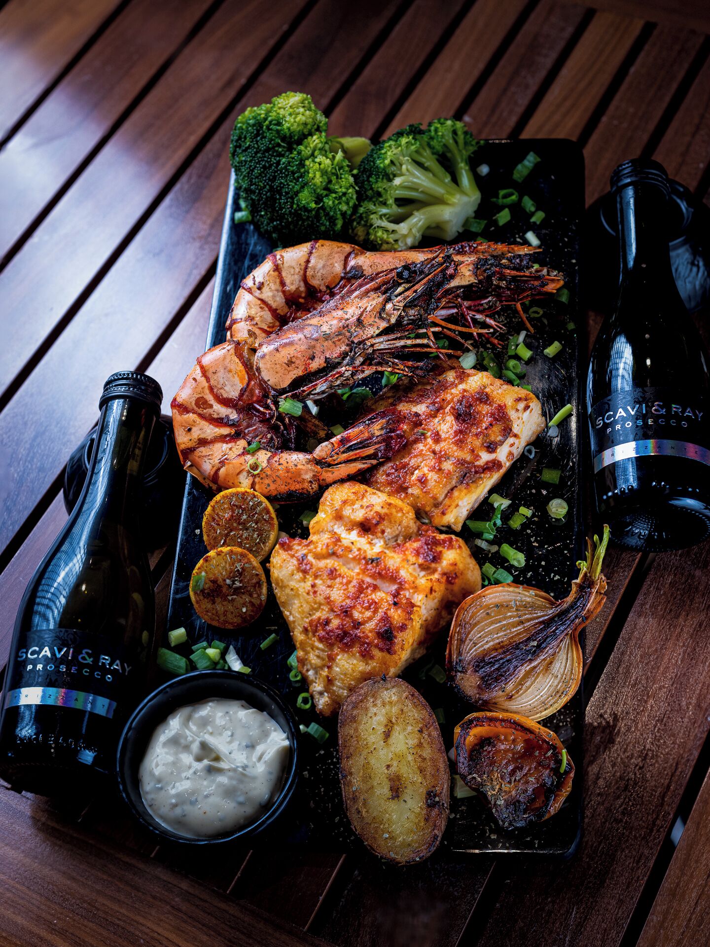 Refeição com frutos do mar, frango e legumes em um prato, acompanhada por duas garrafas de vinho.