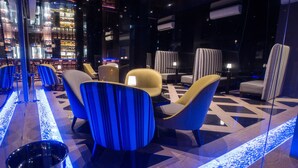 Uma área de estar moderna com cadeiras listradas, um bar com diversos tipos de bebidas e piso estampado.