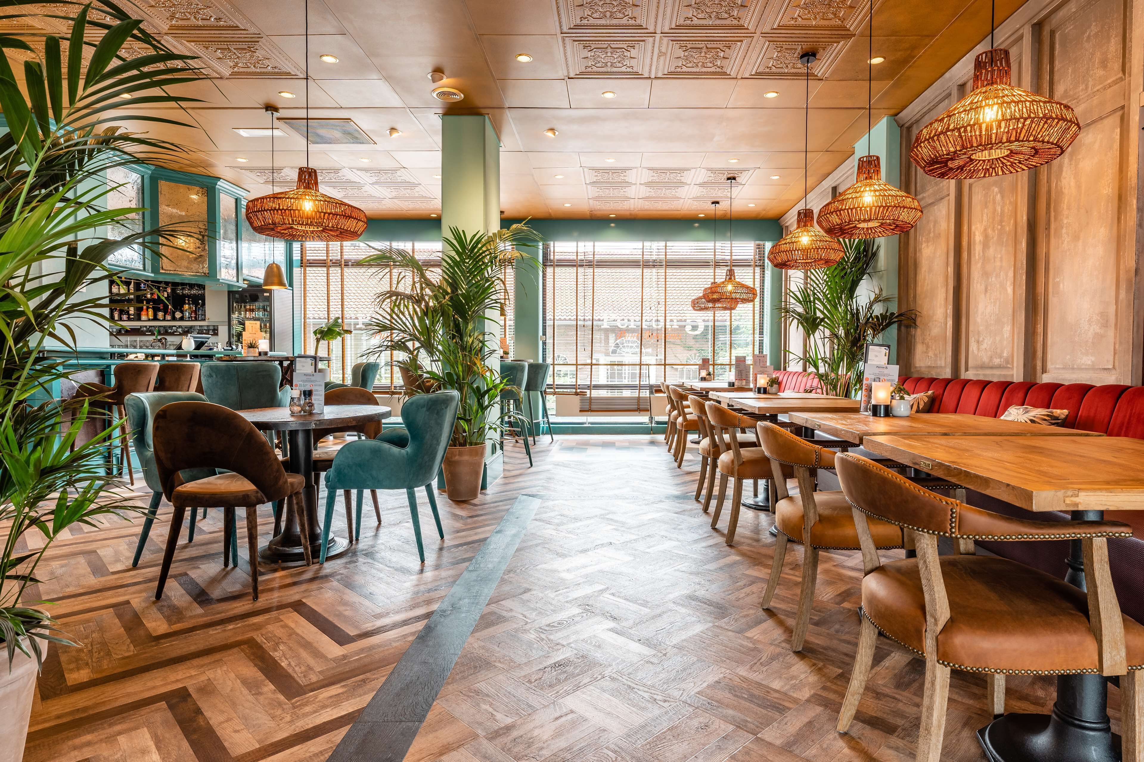 Um restaurante espaçoso com piso de madeira, diversas áreas de estar e lustres de vime pendurados.