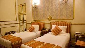 Quarto de hotel com duas camas, um espelho, uma mesa de cabeceira e uma pequena mesa com copos.