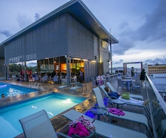 Uma área junto à piscina com espreguiçadeiras e um bar.