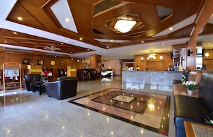 Um saguão de hotel com balcão de recepção, área de estar e piso estampado.