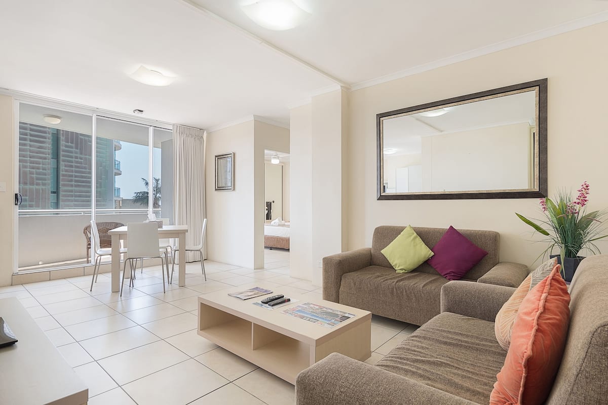 Uma sala de estar moderna com sofá, mesa de centro e área de jantar com cadeiras.