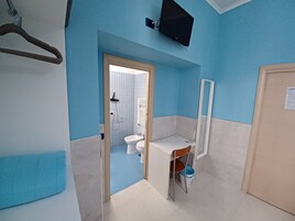 Casa de banho com esquema de cores azul e branco, sanita, pia e zona de duche.