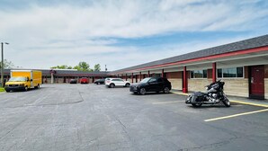 Um motel com estacionamento, vários carros estacionados e uma motocicleta.