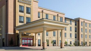 Um hotel Comfort Inn & Suites com fachada de tijolos, porta de entrada vermelha e área frontal coberta.