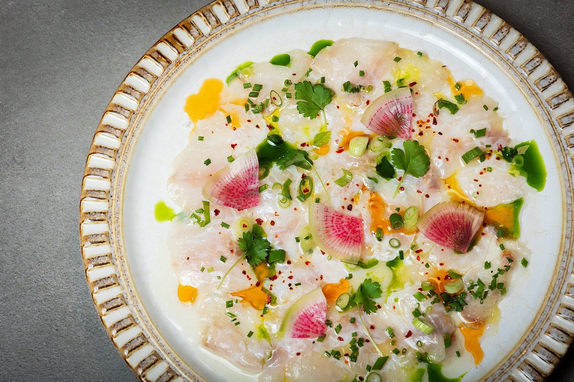 Um prato de sashimi com diversos acompanhamentos.