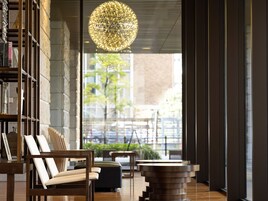Um interior moderno com uma estante de madeira, uma luminária pendente redonda e uma área de estar com uma mesa redonda.
