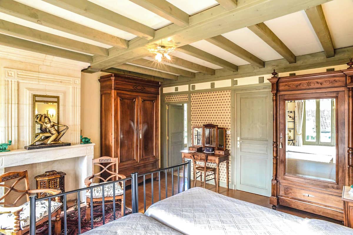 Quarto com cama grande, guarda-roupa de madeira e escrivaninha com espelho.