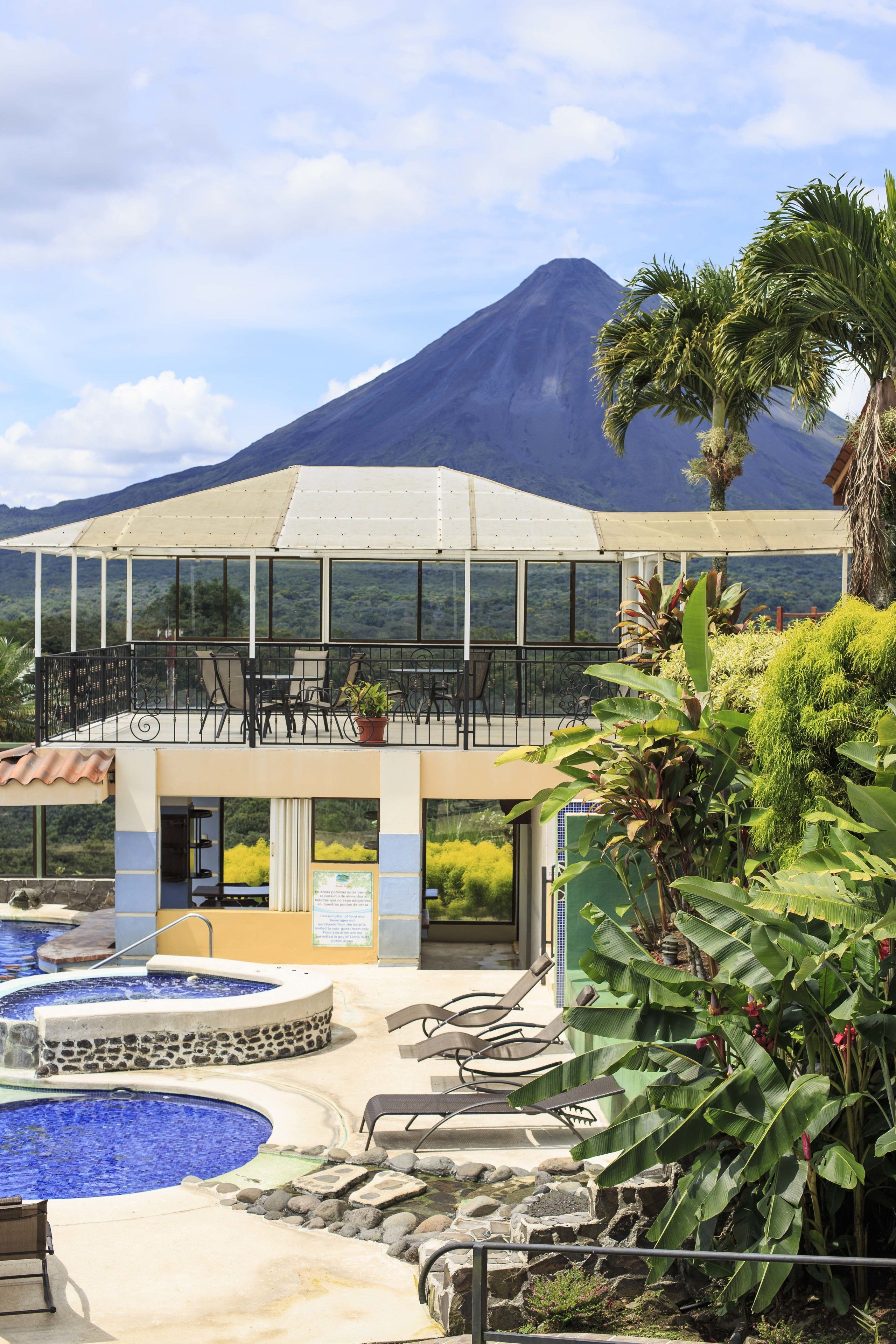 Um hotel com área de piscina, espaço para sentar ao ar livre e vista para um vulcão.