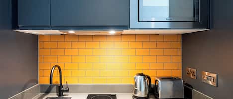 Cozinha moderna com micro-ondas integrado, chaleira e torradeira.