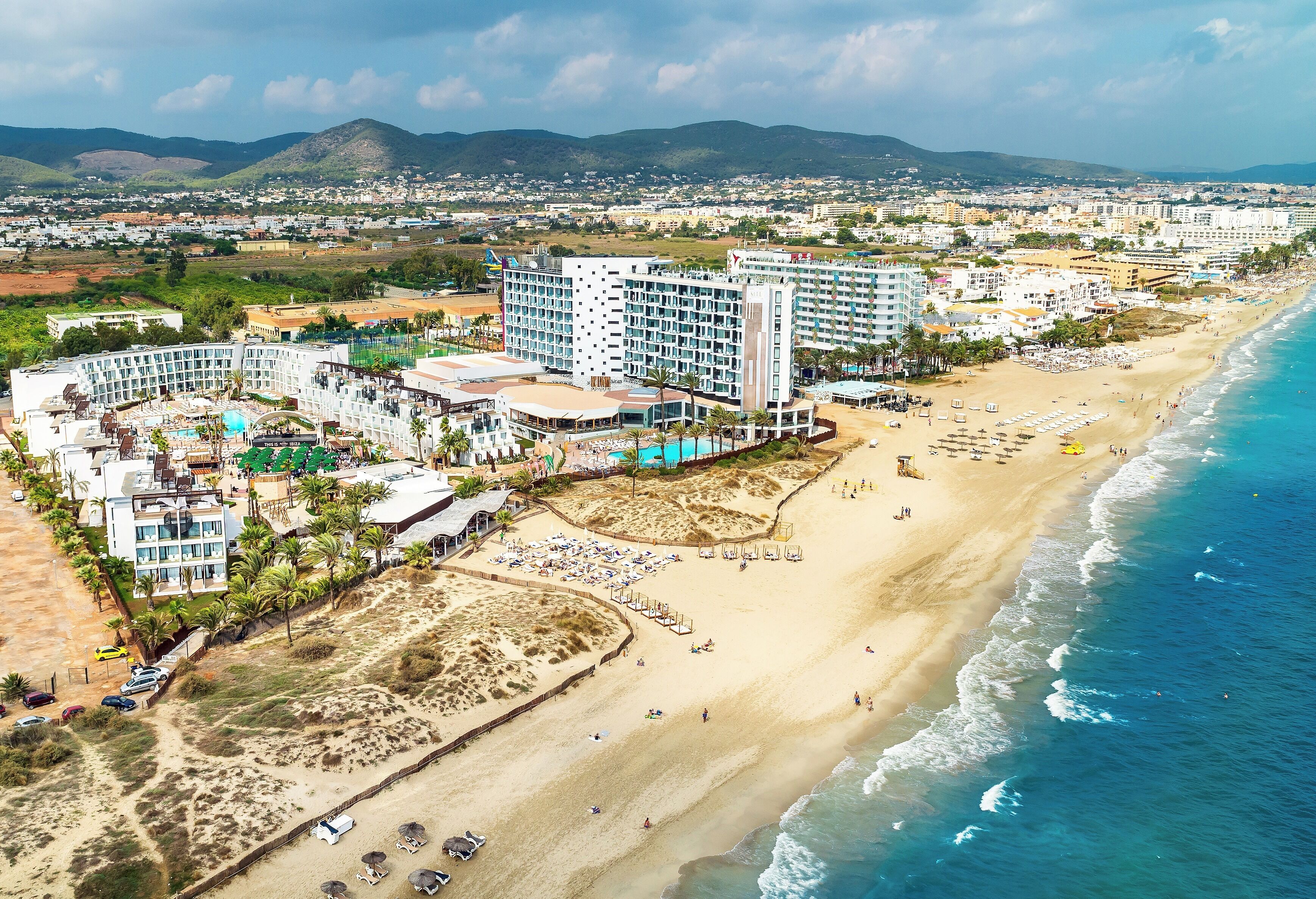 Um hotel à beira-mar com vários edifícios, uma praia de areia e vista para o oceano.
