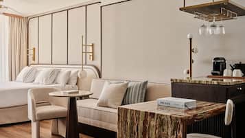 Quarto de hotel moderno com cama, sofá, mesa redonda e cantinho de café.
