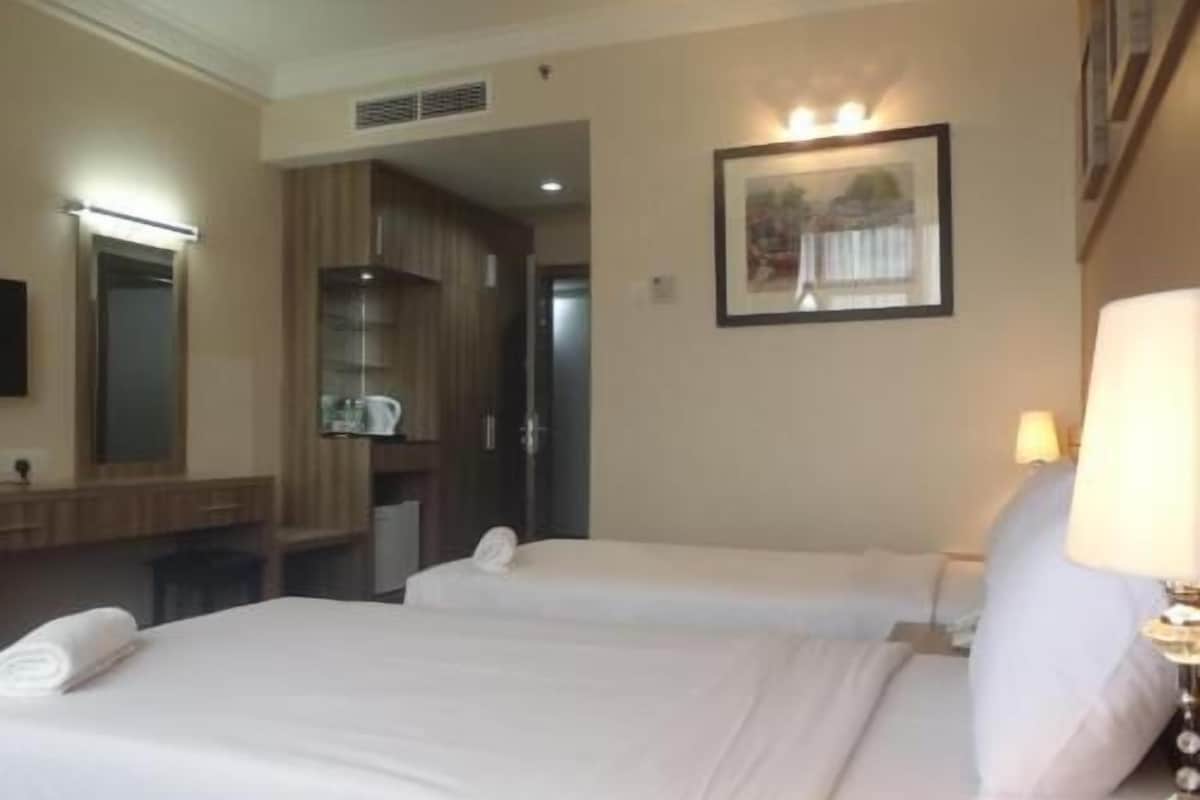 Quarto de hotel com duas camas, banheiro e área de refeições.