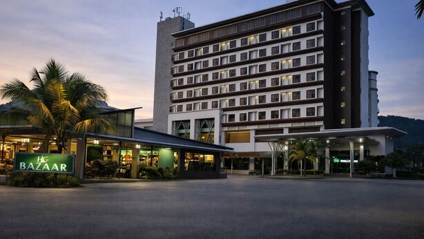 Um hotel com vários andares, com uma placa grande de 'HG BAZAAR', design moderno e entrada bem iluminada.