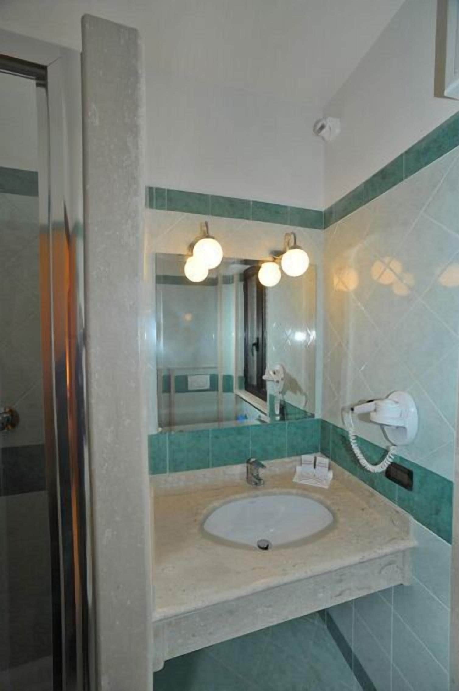Uma casa de banho com lavatório, espelho e secador de cabelo.