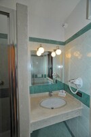 Uma casa de banho com lavatório, espelho e secador de cabelo.