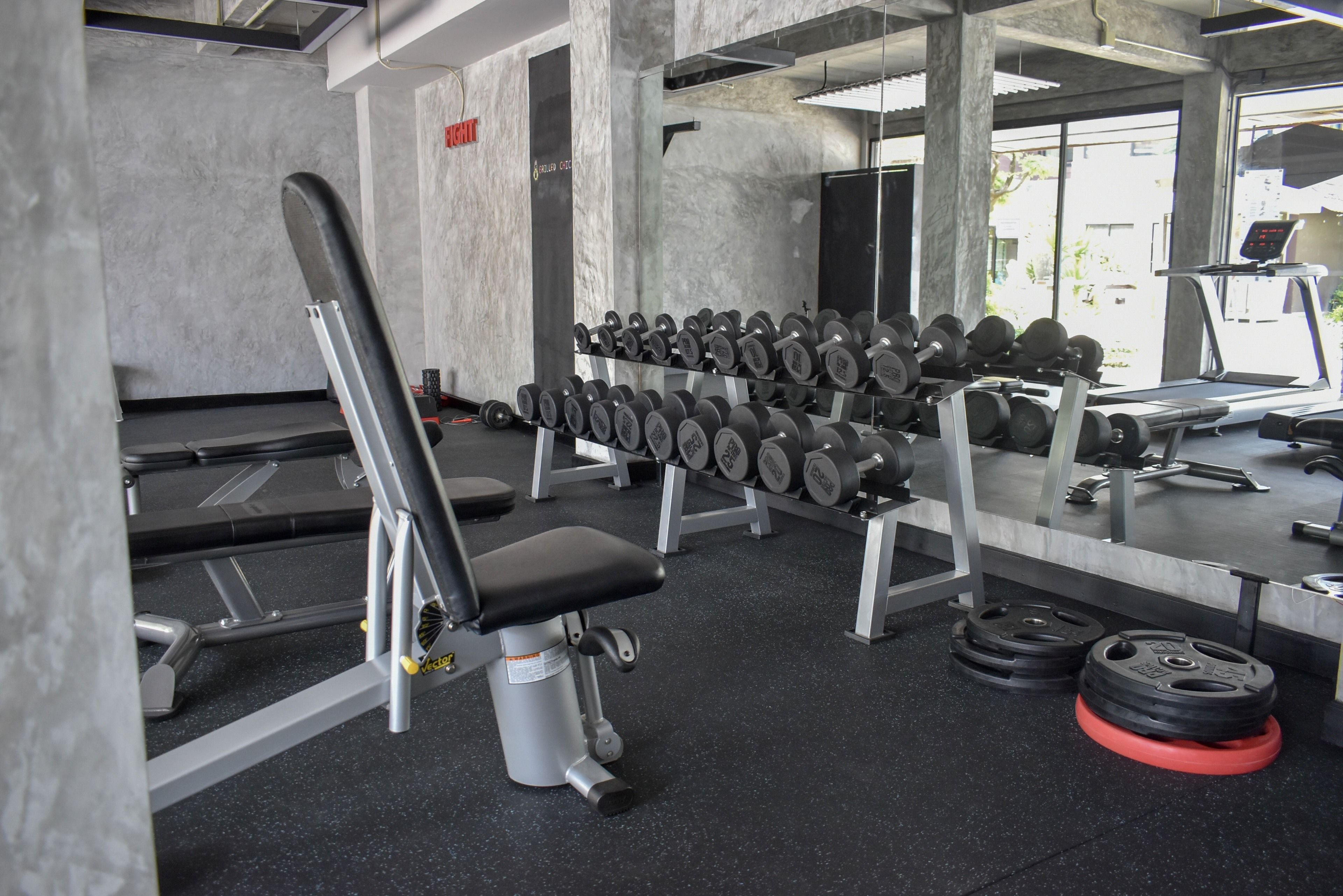Uma academia com equipamentos de musculação, esteiras e um banco.