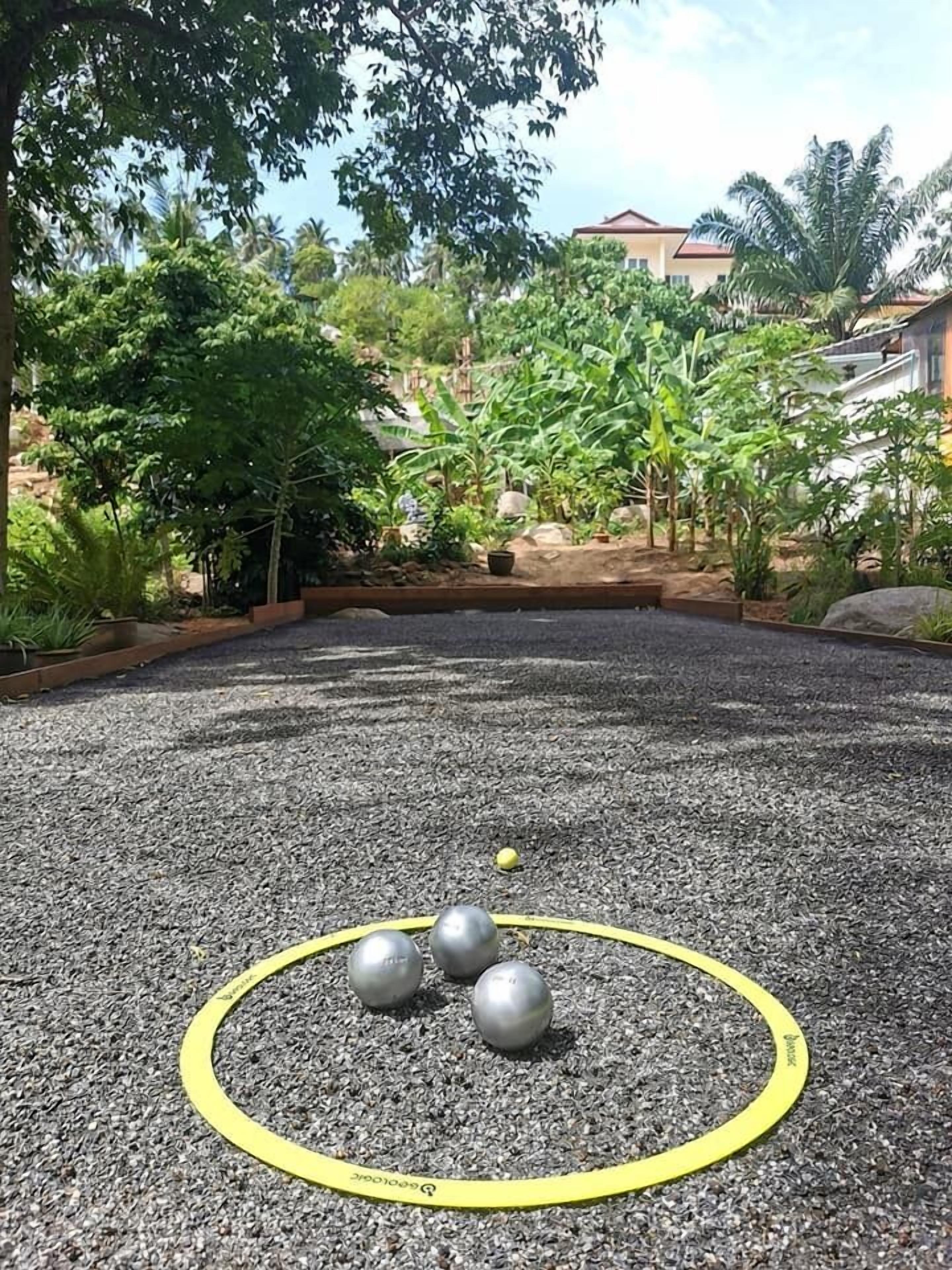 Uma área de cascalho com três esferas metálicas e uma linha divisória amarela.